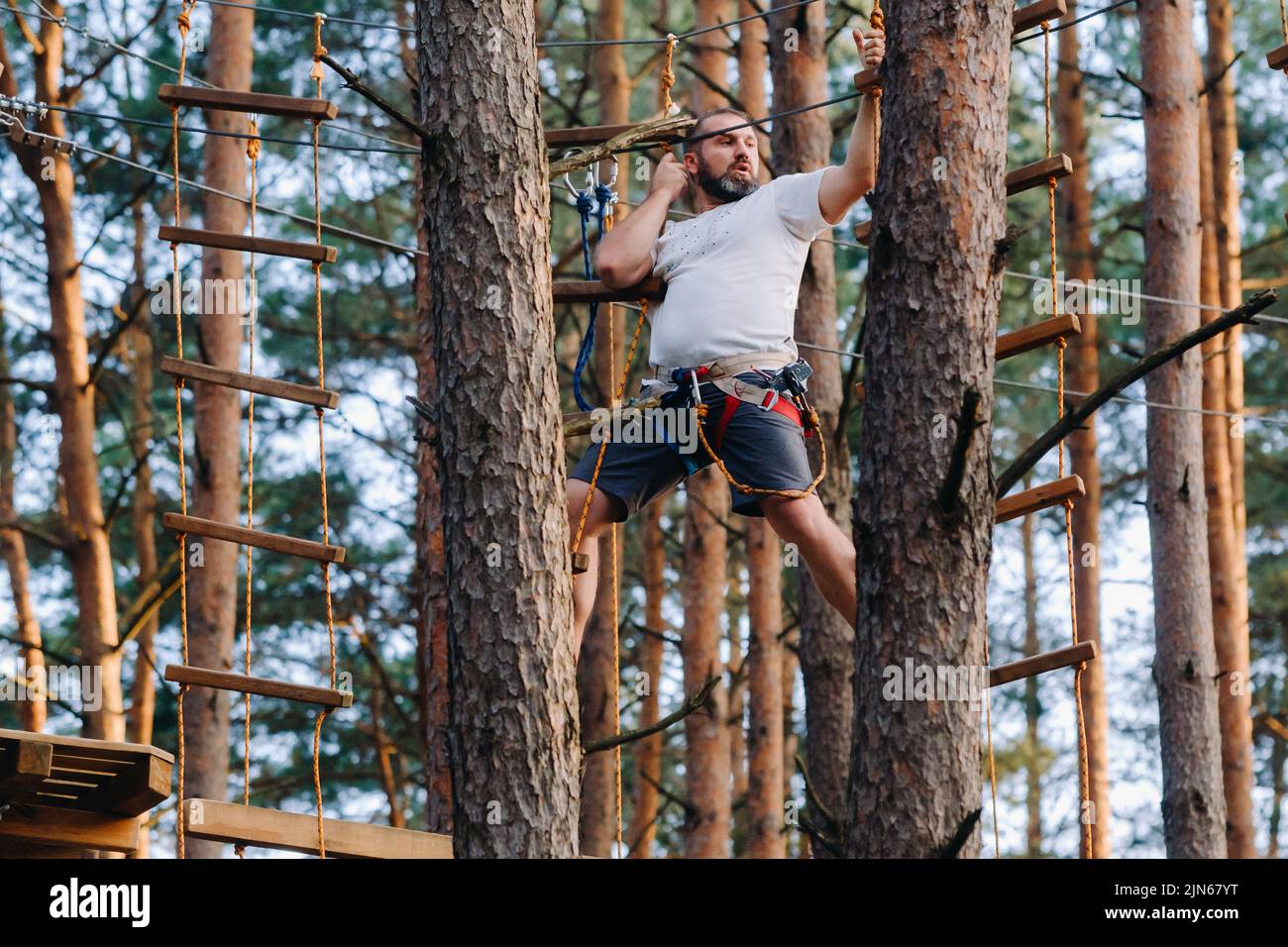 A man overcomes an obstacle in a rope town. A man in a forest rope park ...