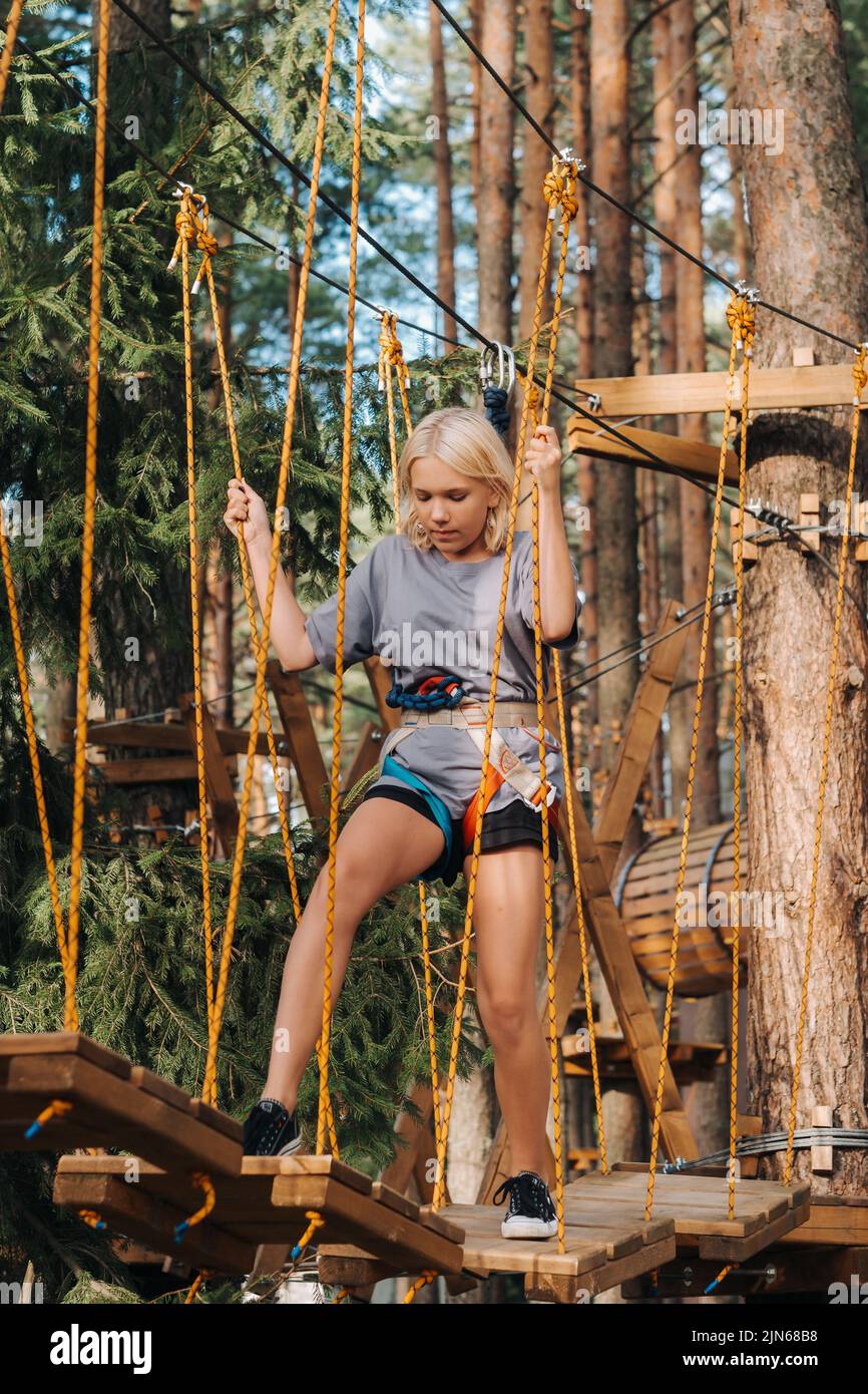 A girl passes an obstacle in a rope town. A girl in a forest rope park ...