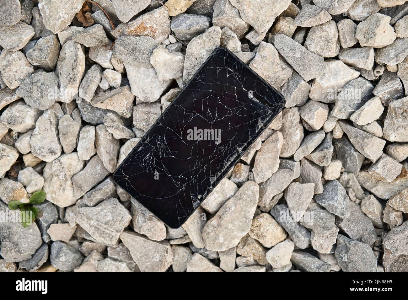 Black smartphone with broken display on the stones. Phone screen damage ...
