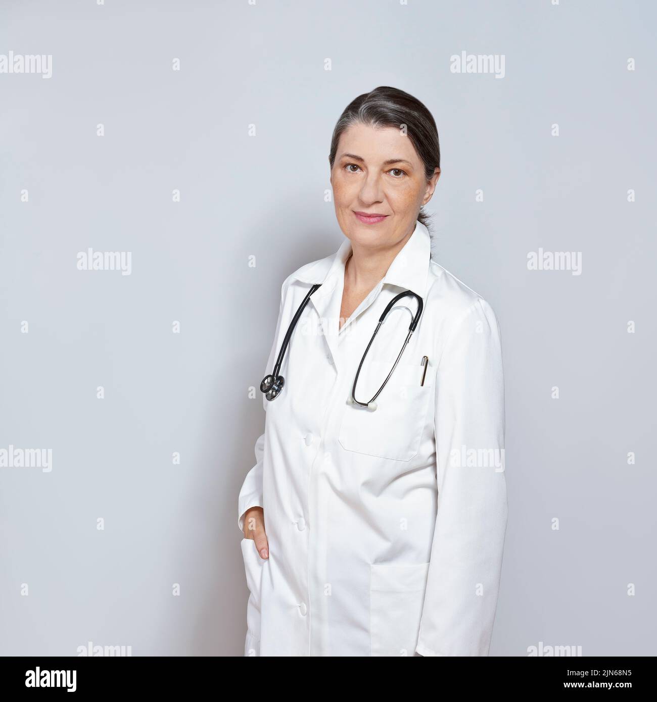 Middle aged female doctor in a white lab coat, smiling friendly, on ...