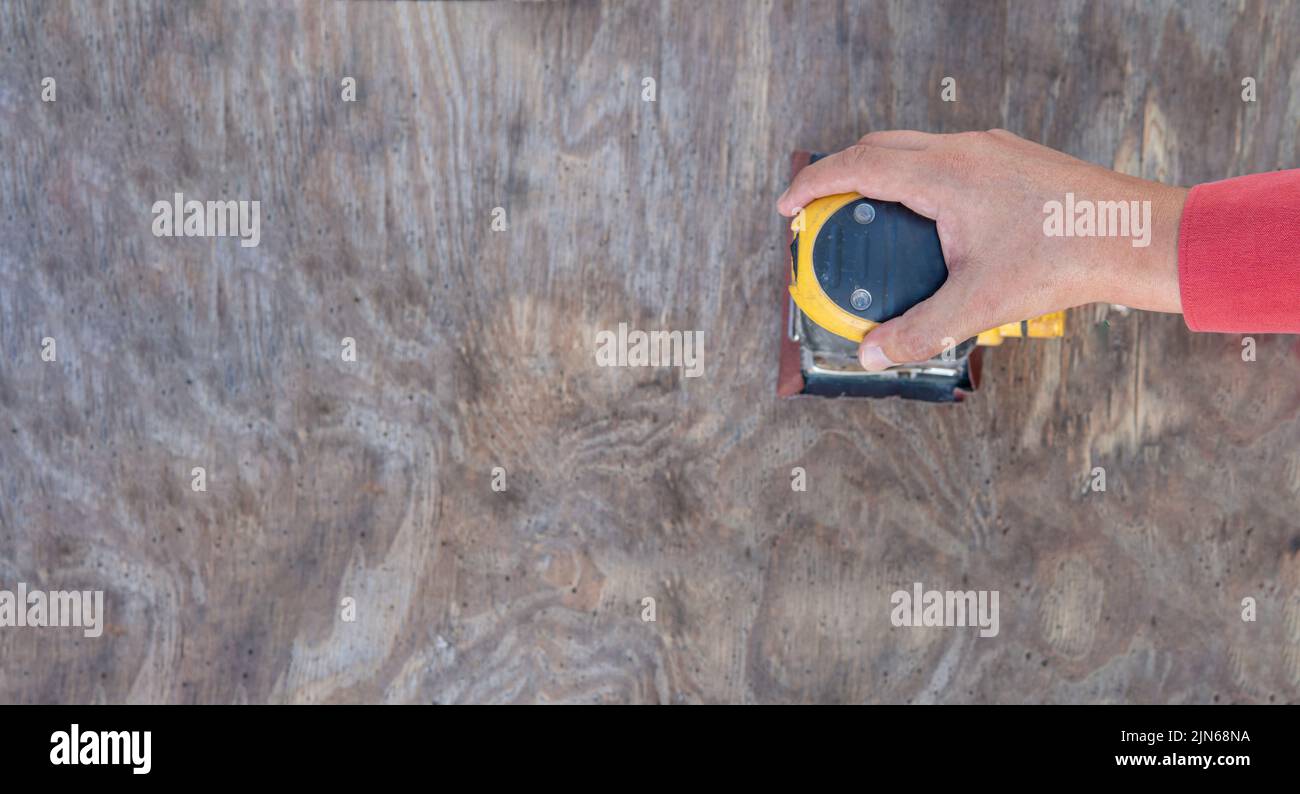 overview photo of a man's hand with an electric sander on a wooden ...