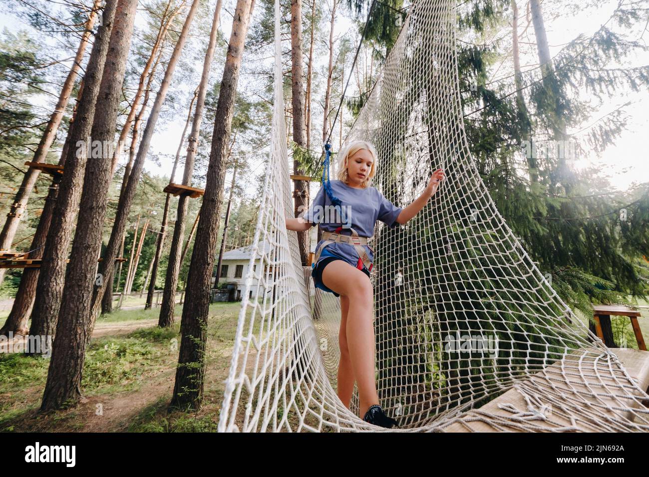A girl passes an obstacle in a rope town. A girl in a forest rope park ...