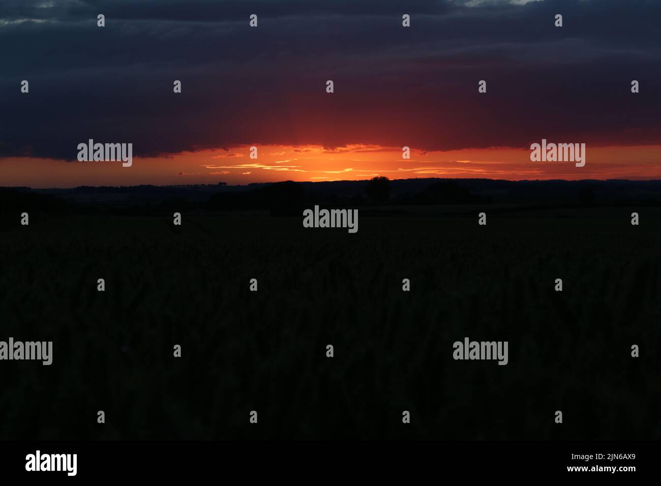 Line of red sunset between horizon and dark clouds Stock Photo - Alamy