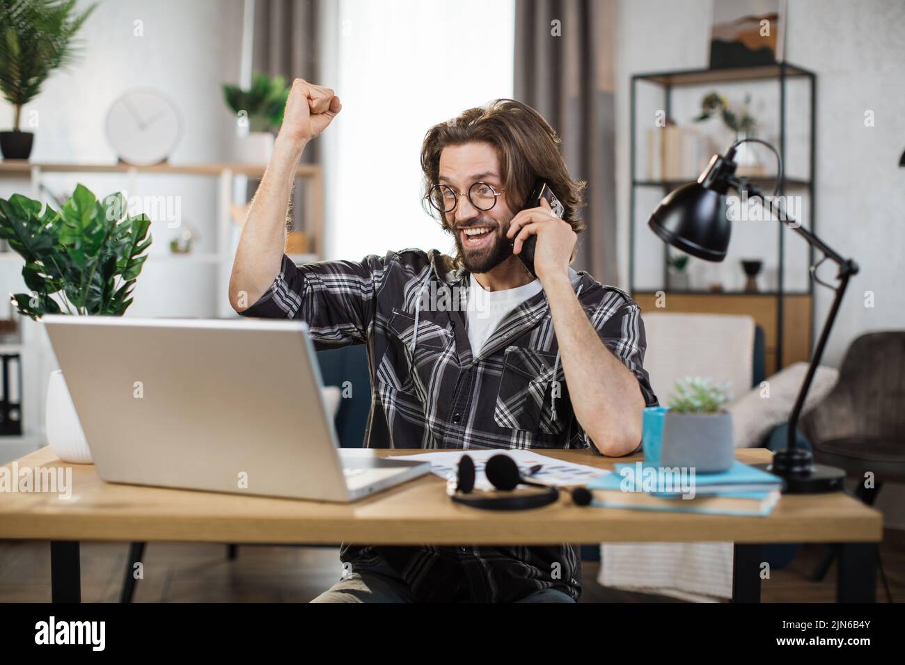 Excited caucasian businessman sitting at table using modern laptop and ...