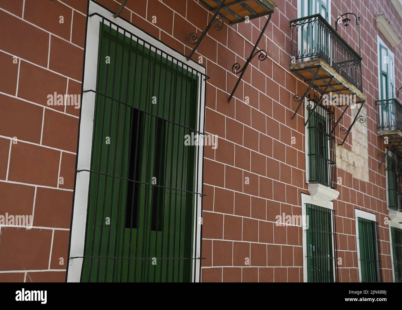 Old Colonial building facade with a ceramic tile wall and green wooden ...