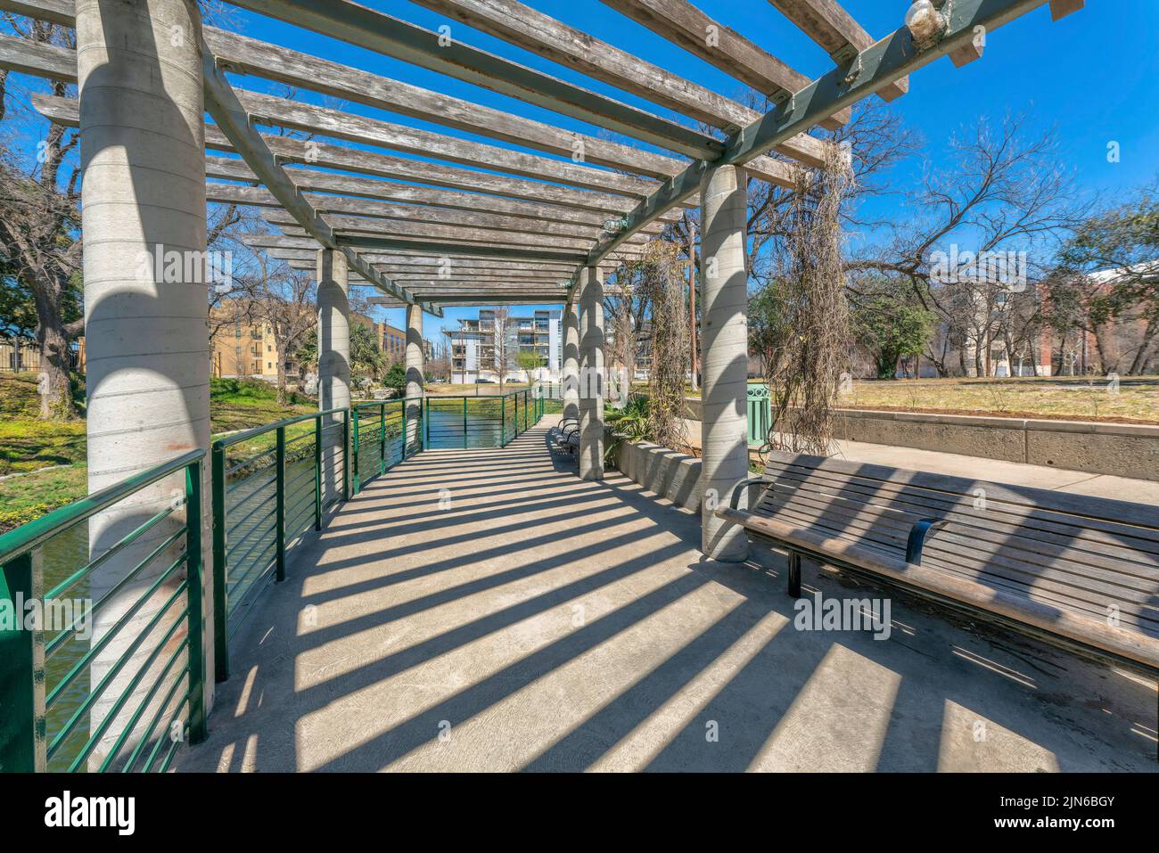 Concrete walkway with pergola and bench near the river at San Antonio ...