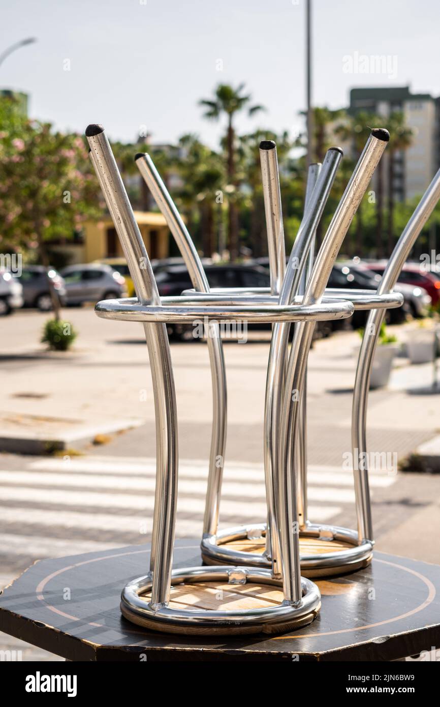 A vertical shot of two metallic chairs placed upside down on a table ...
