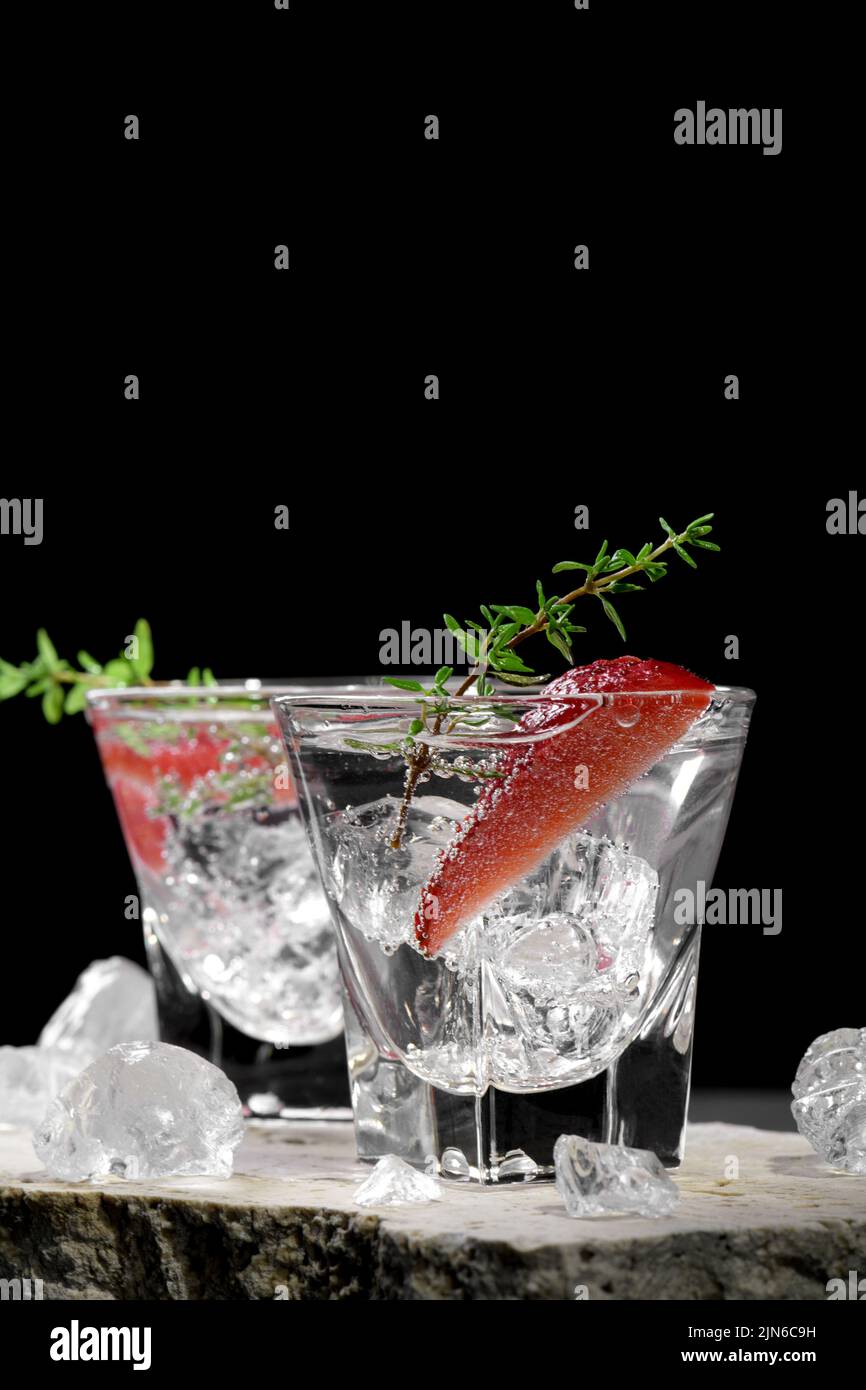 Vodka in two shot glass with ice, decorated with strawberry slice and ...