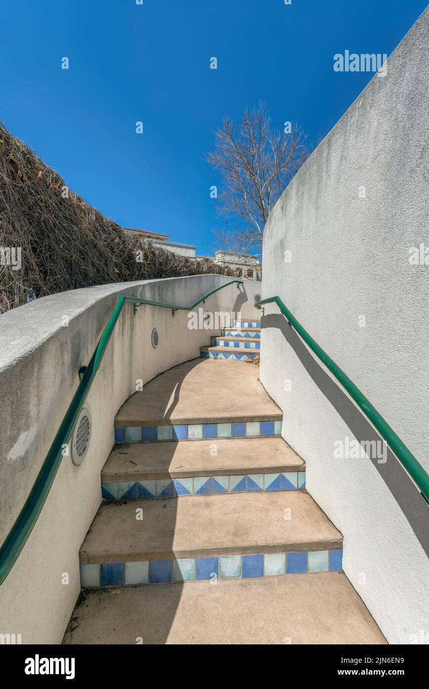 Outdoor stairs with blue tile risers and wall-mounted green handrails ...