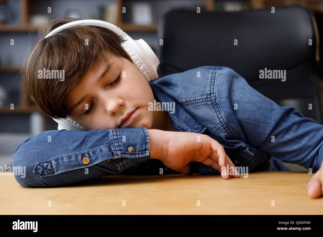 Young boy studying remotely at home using laptop. Tired schoolboy ...