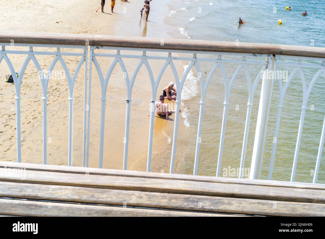 Two people, a man and a woman sitting in the water on the beach of ...