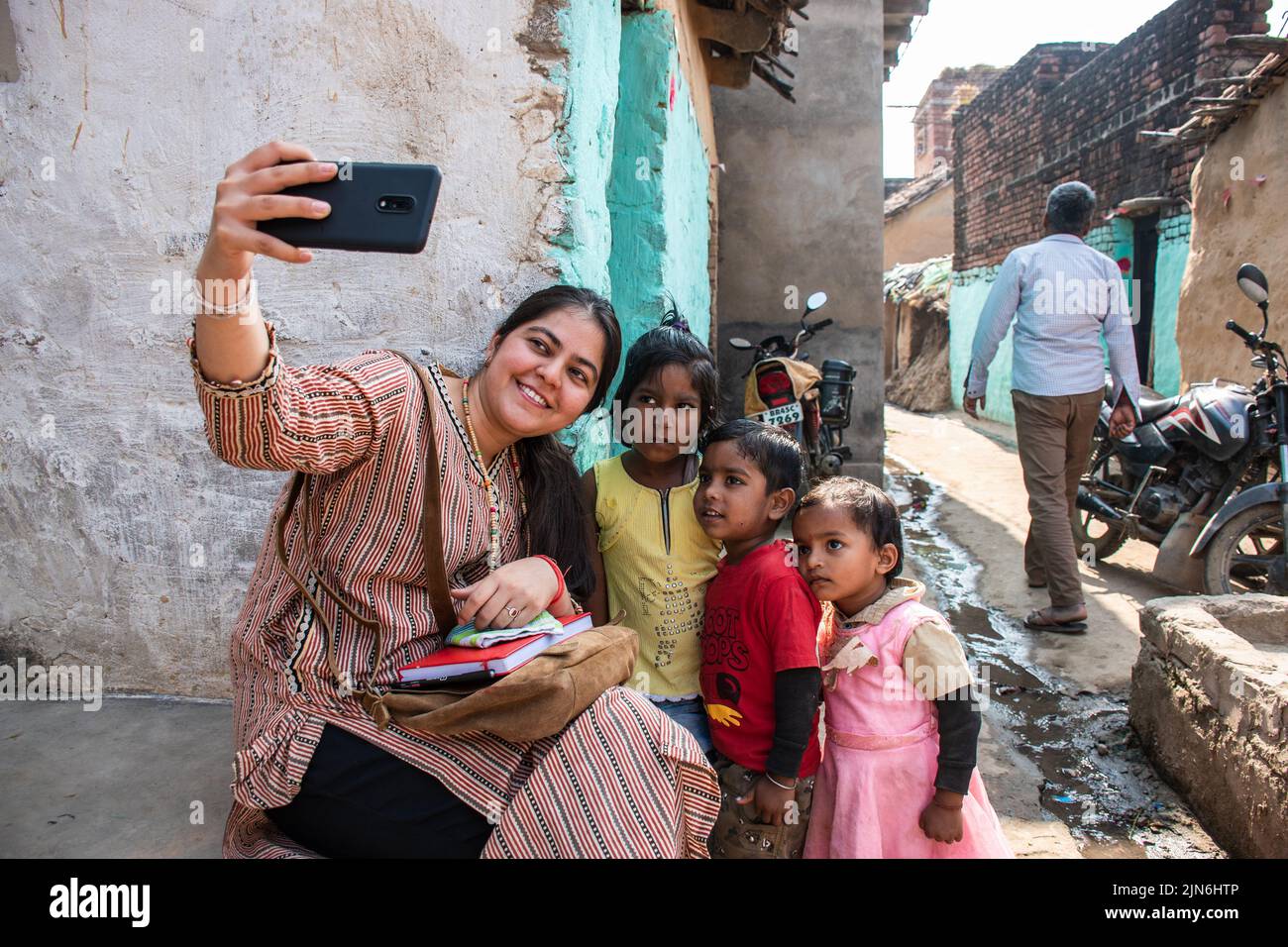 A social worker is taking a selfie with young girls collecting garbage ...