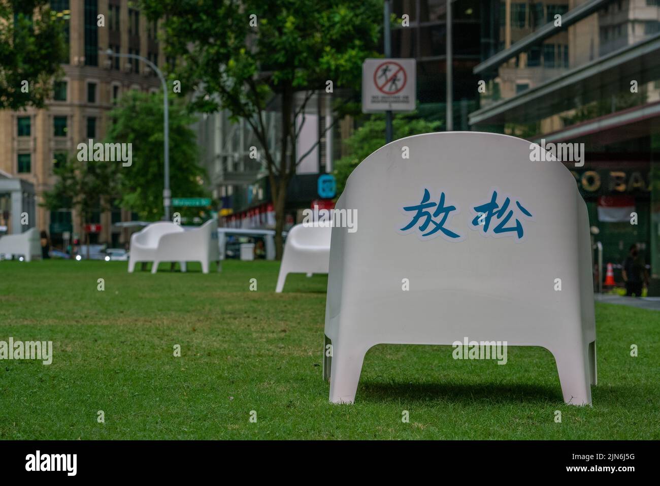 White chair with 'Relax' written in Chinese in a public park at Raffles ...
