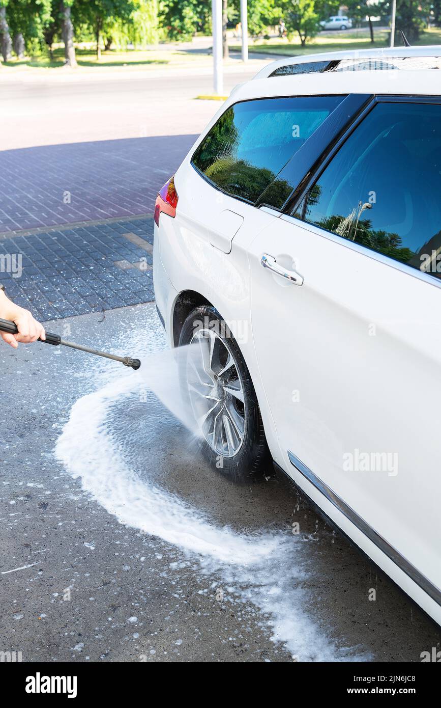 Hand washing with high pressure water in a car wash outside. A jet of ...