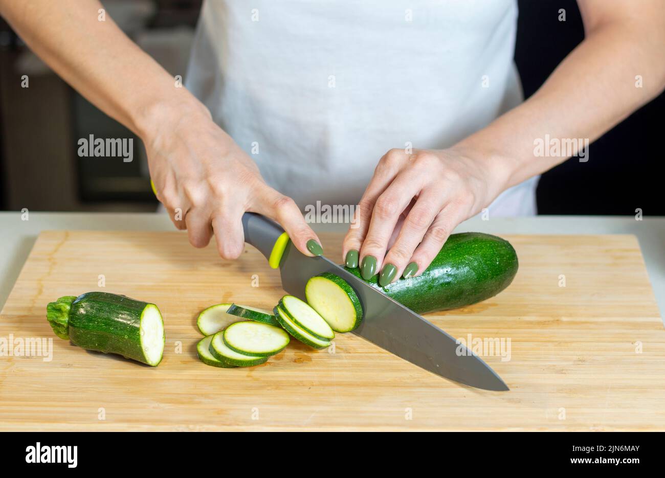 Close up of young woman hands cutting zucchini on wooden cutting Stock ...