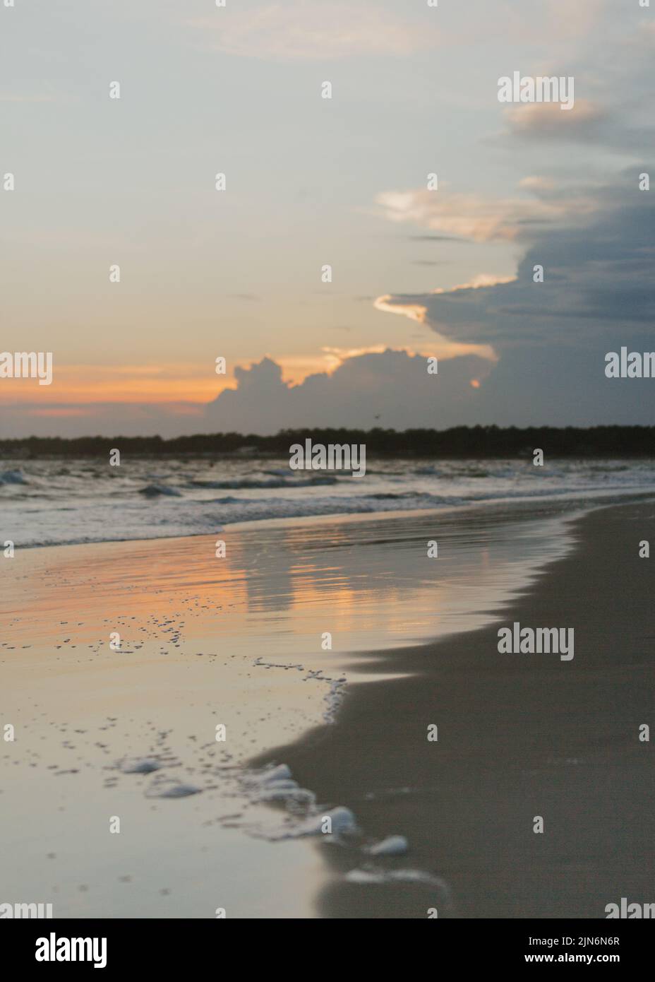 Partly cloudy sunset reflection where water meets the sand on the ...