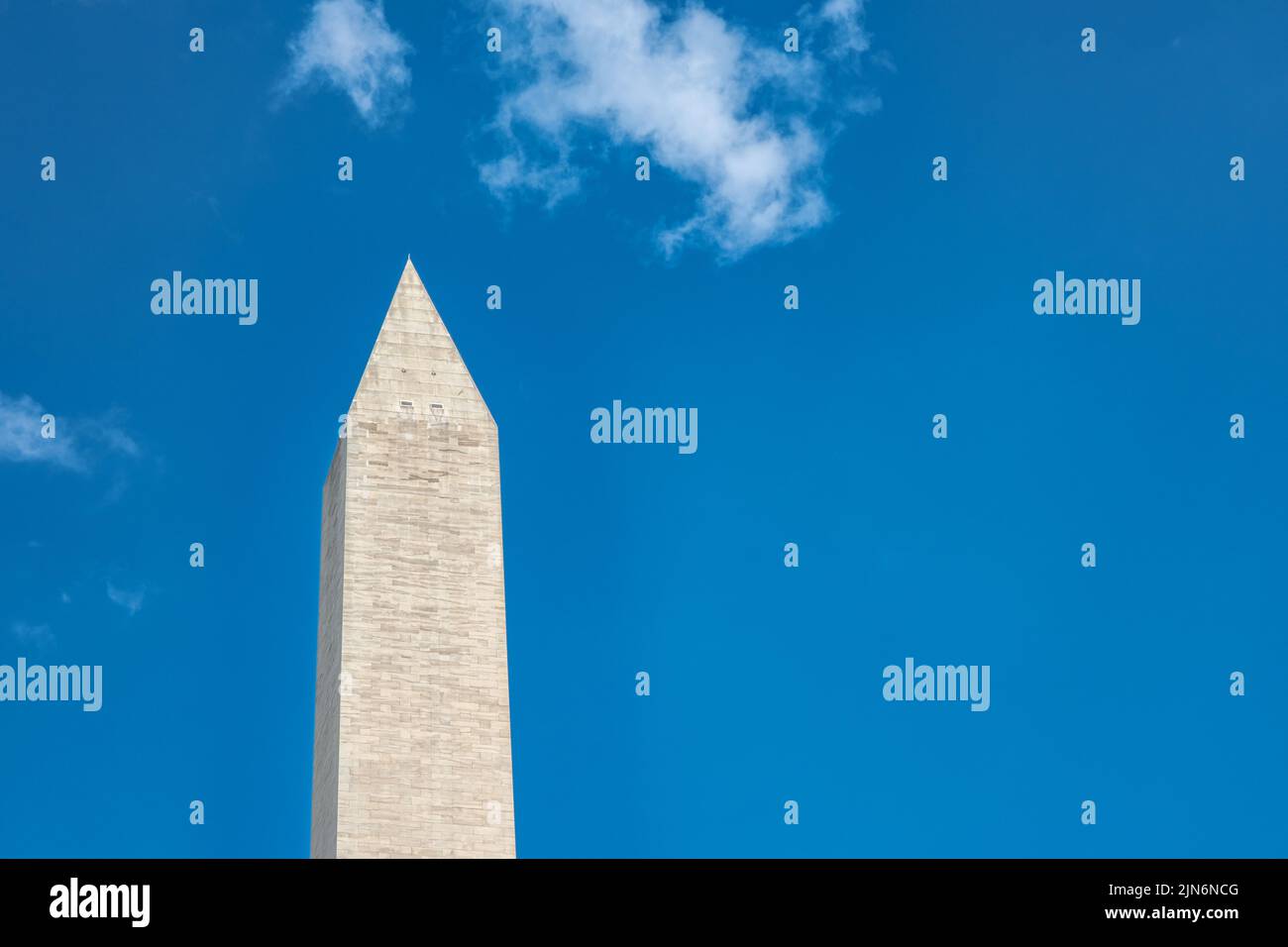 Top of the Washington Monument stands out against a blue sky with a ...