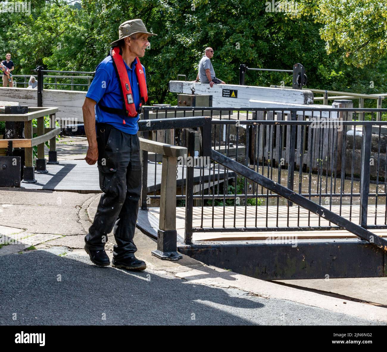A Canal and River Trust lock keeper turning a swing bridge at the top ...