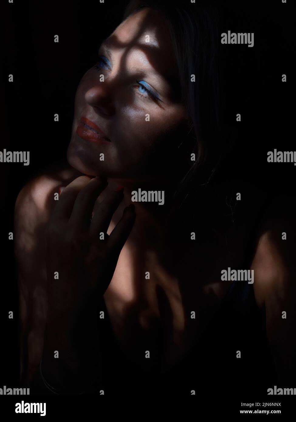 Portrait of a young woman in the dark with partial natural light ...