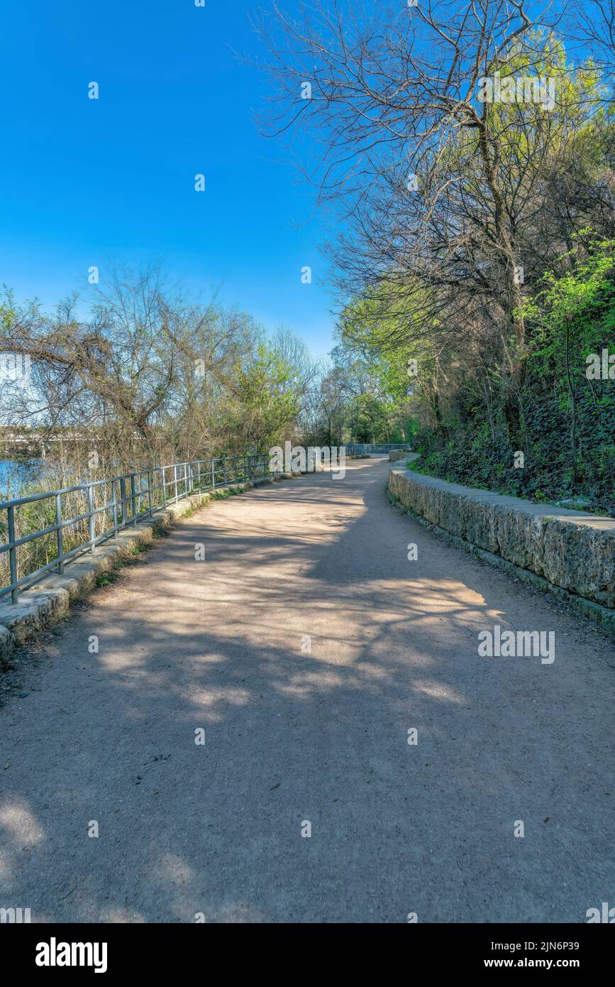 Flat dirt path with metal railings near the slope with concrete wall at ...