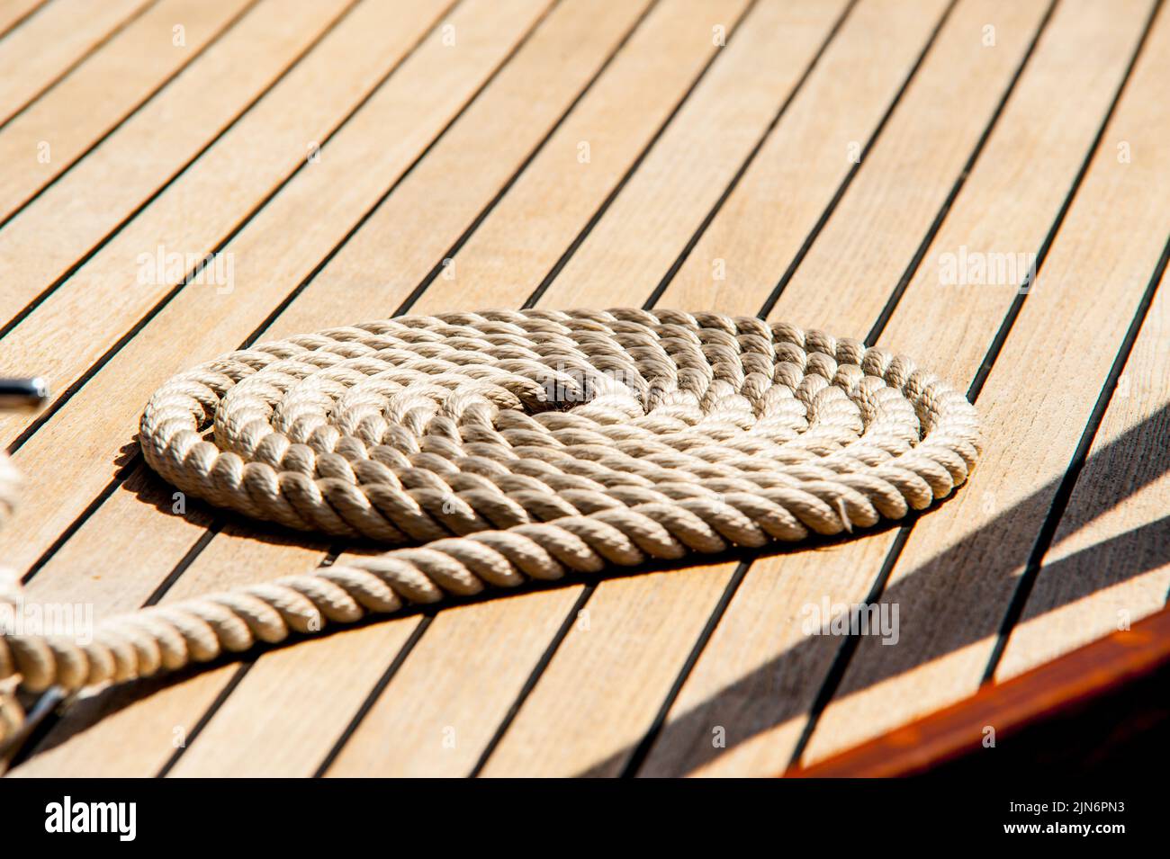 A rope neatly coiled on the wooden deck of a boat Stock Photo - Alamy