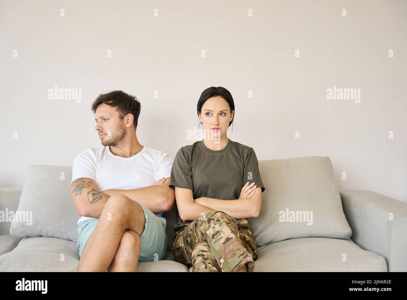 Conflicting couple sitting on sofa in closed poses Stock Photo - Alamy