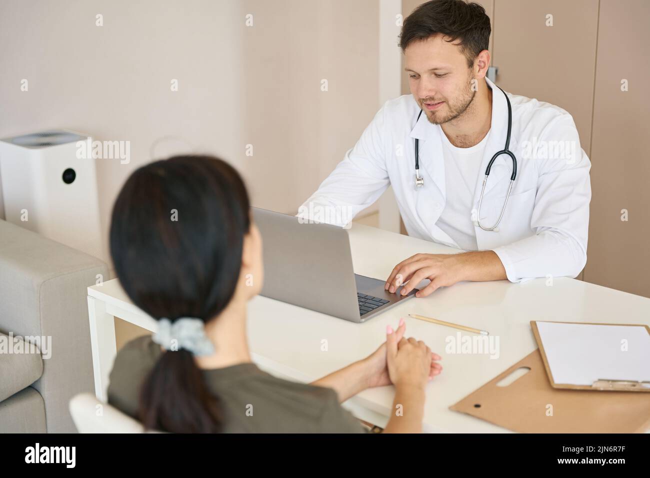 Doctor with a phonendoscope interrogates a patient about health ...
