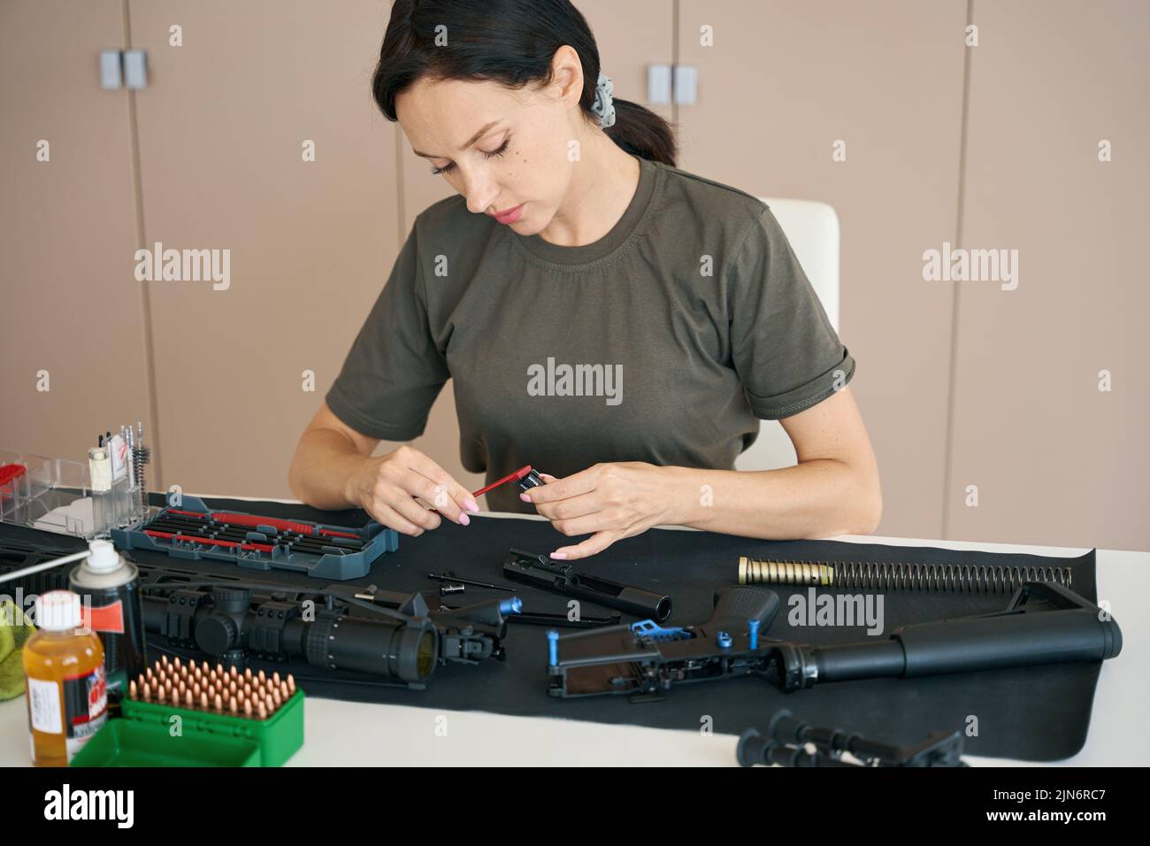 Military woman cleaning weapons at the table Stock Photo - Alamy