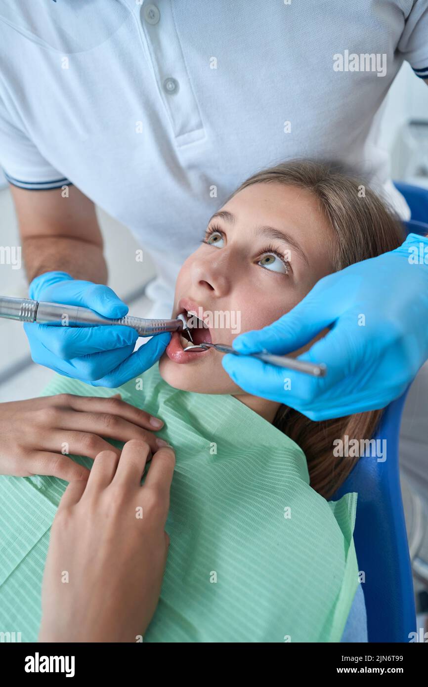 Stomatologist performing cavity preparation procedure in teenage ...