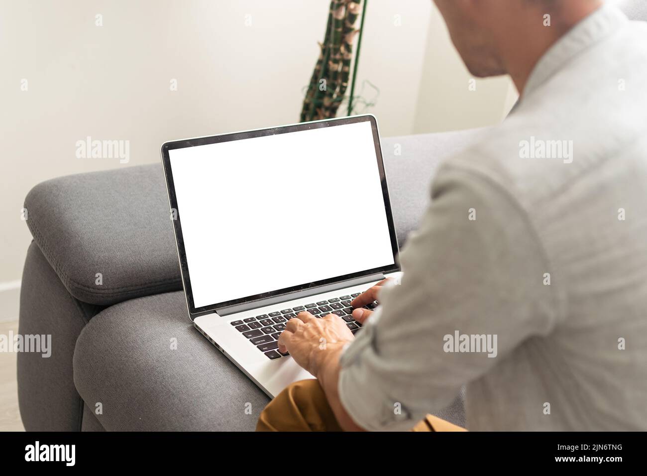 Young male tech user relaxing on sofa holding laptop computer mock up ...