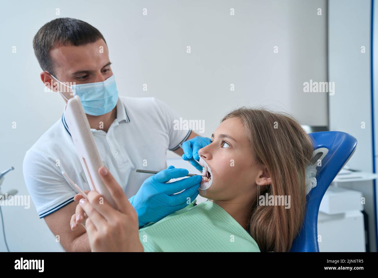 Male doctor checking teeth of adolescent girl Stock Photo - Alamy