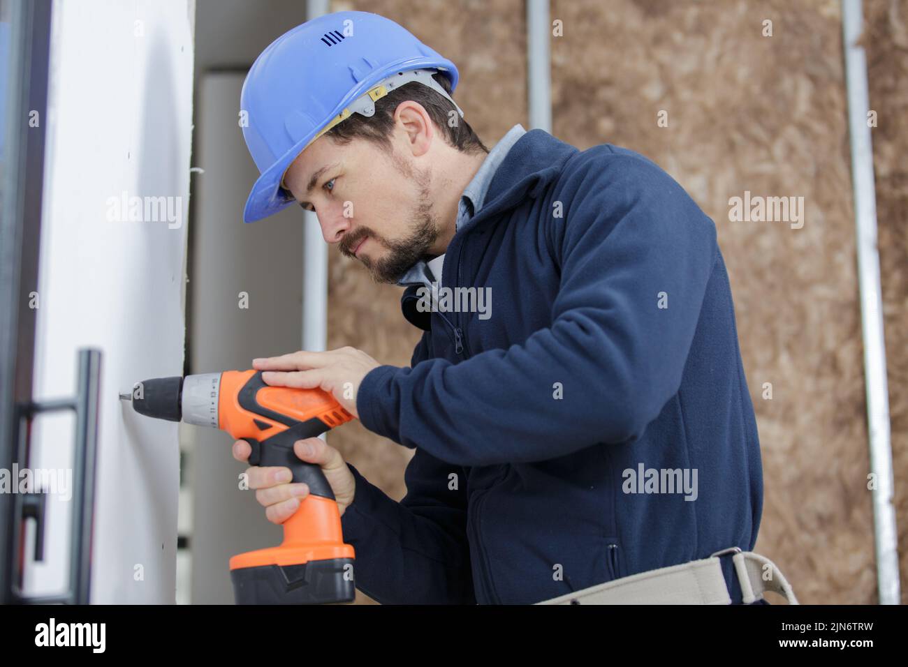 construction worker using drill to install door Stock Photo - Alamy