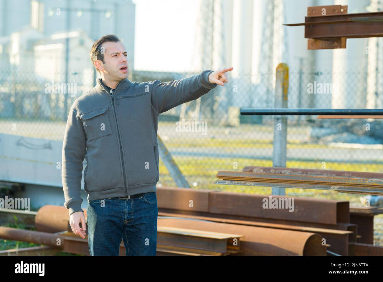man in industrial yard pointing into distance and shouting out Stock ...