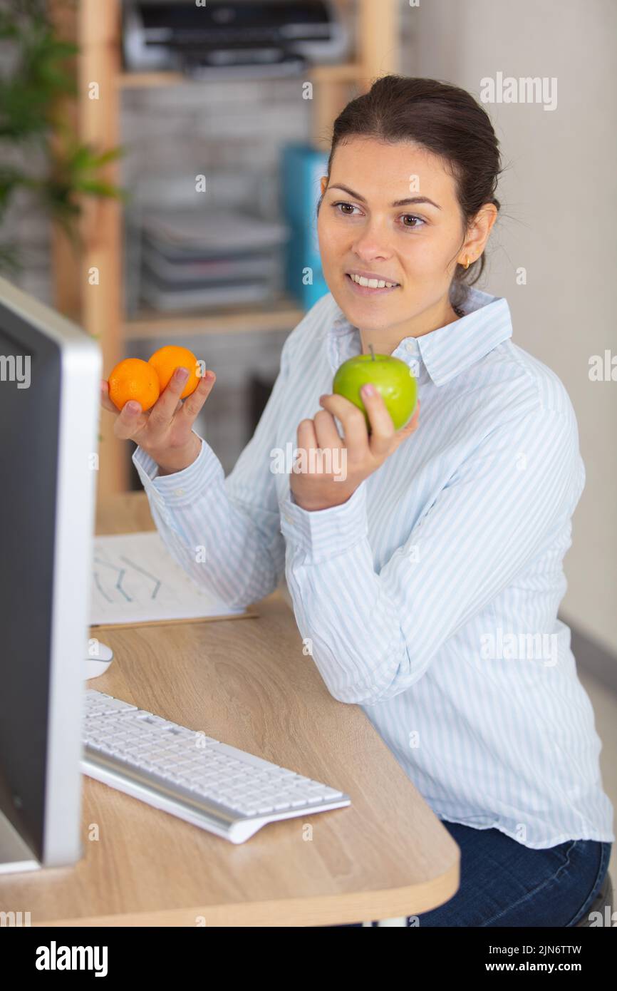 cute woman snacking on fruits in office Stock Photo - Alamy
