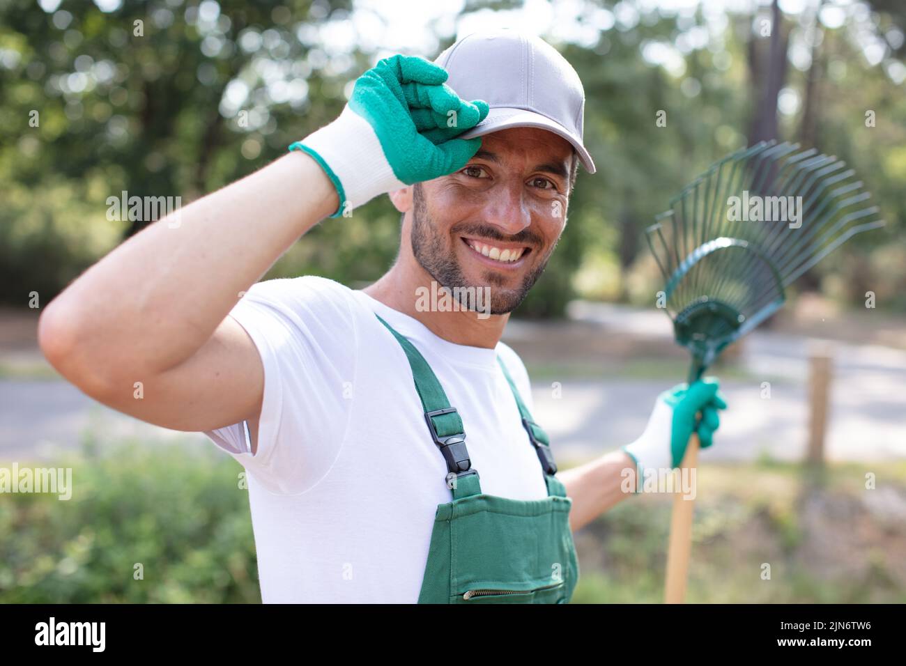 friendly male gardener with rake tipping his cap in greeting Stock ...