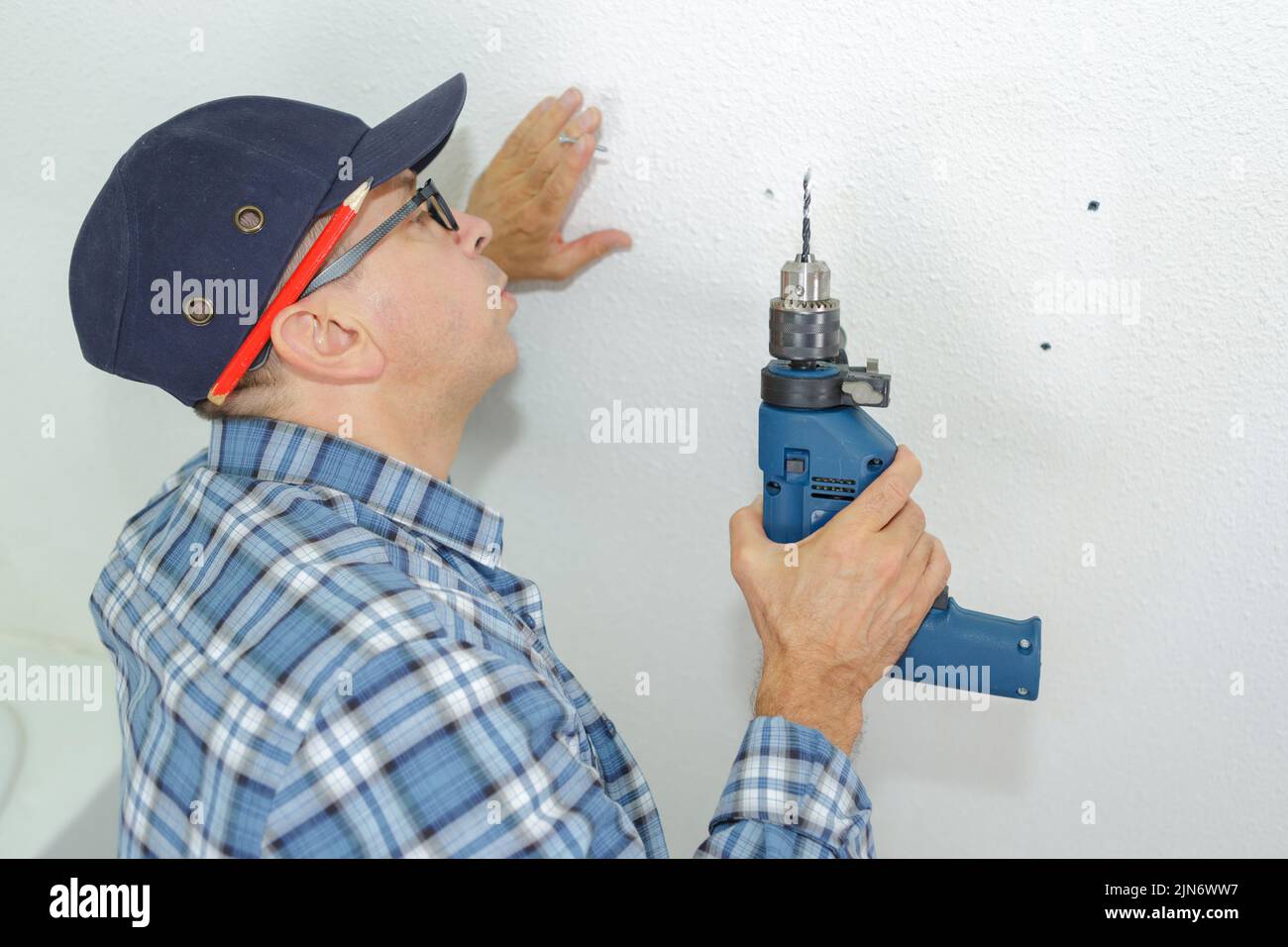 man drilling the wall with drill perforator Stock Photo - Alamy