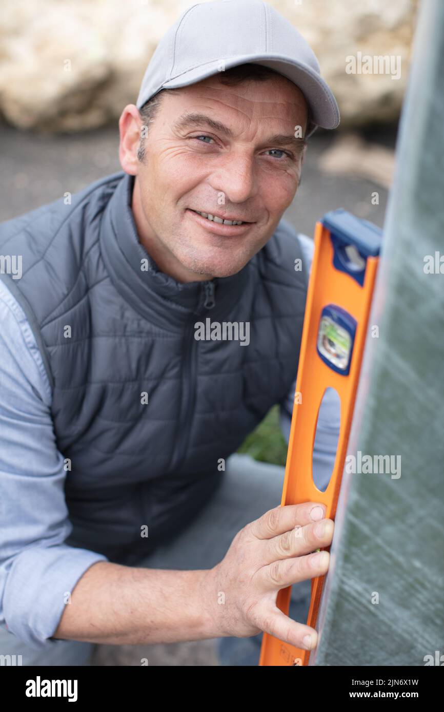 fence construction - worker check the level of metal post Stock Photo ...