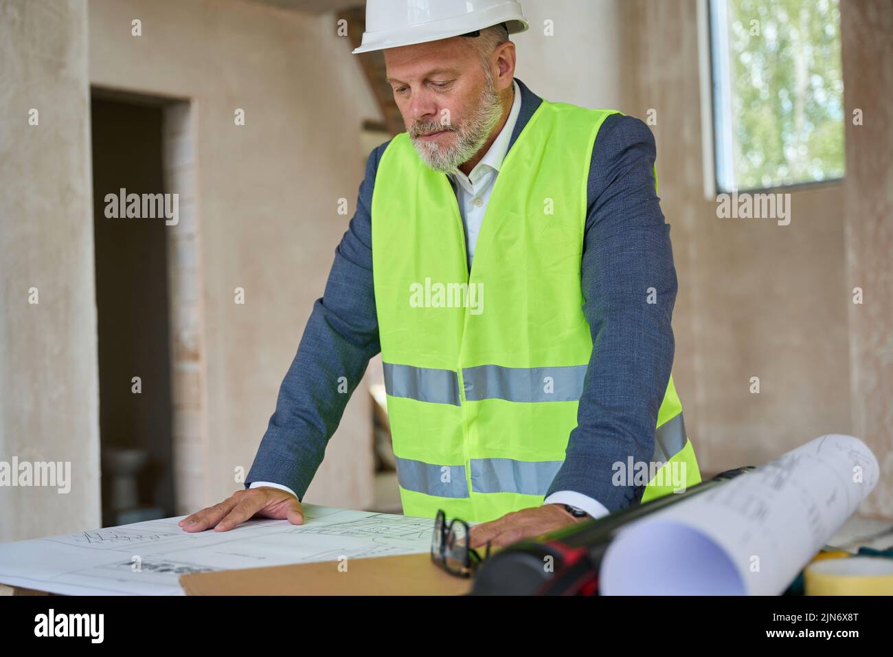 Respectable foreman in suit looks at drawing on table Stock Photo - Alamy