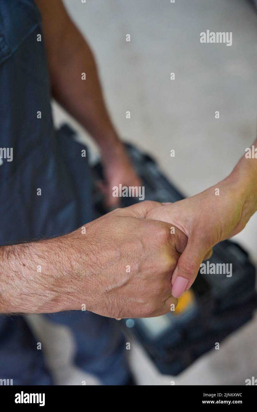 Female hand shakes builder hand against background of tool box Stock ...