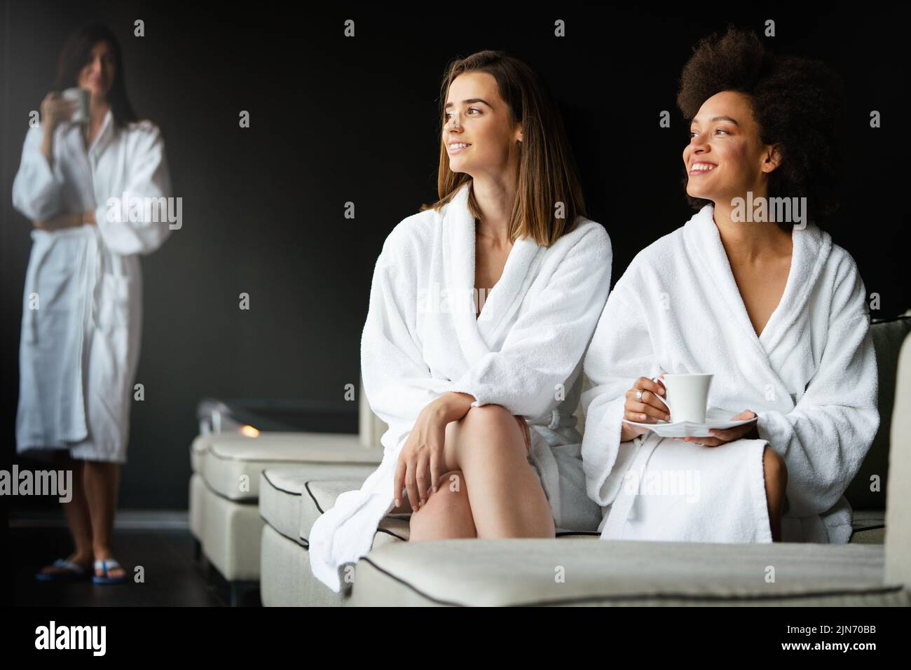Portrait of happy cheerful girl in robe talking with her friend Stock ...