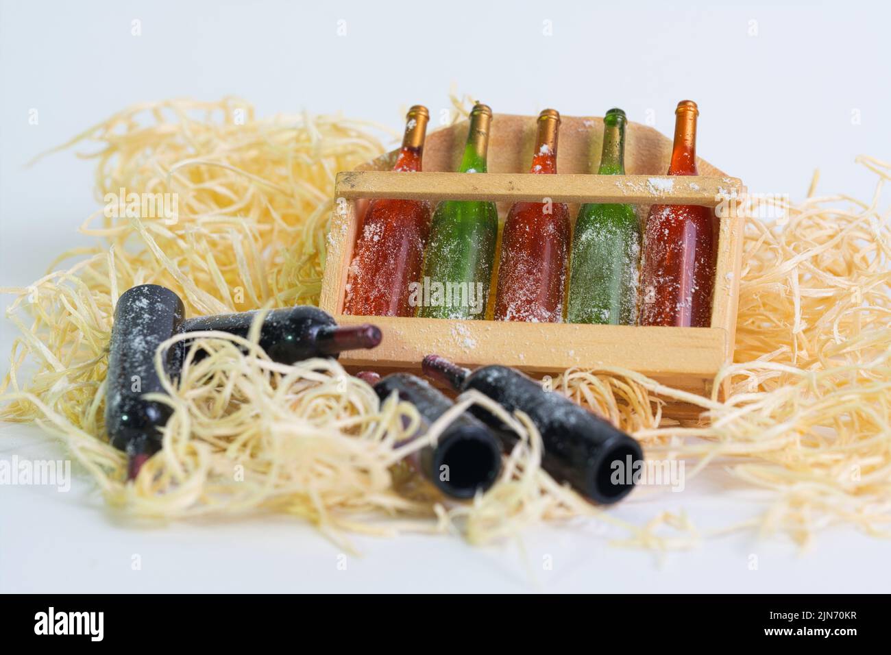 dusty wine bottles in a wooden rack on straw, other bottles are next to ...