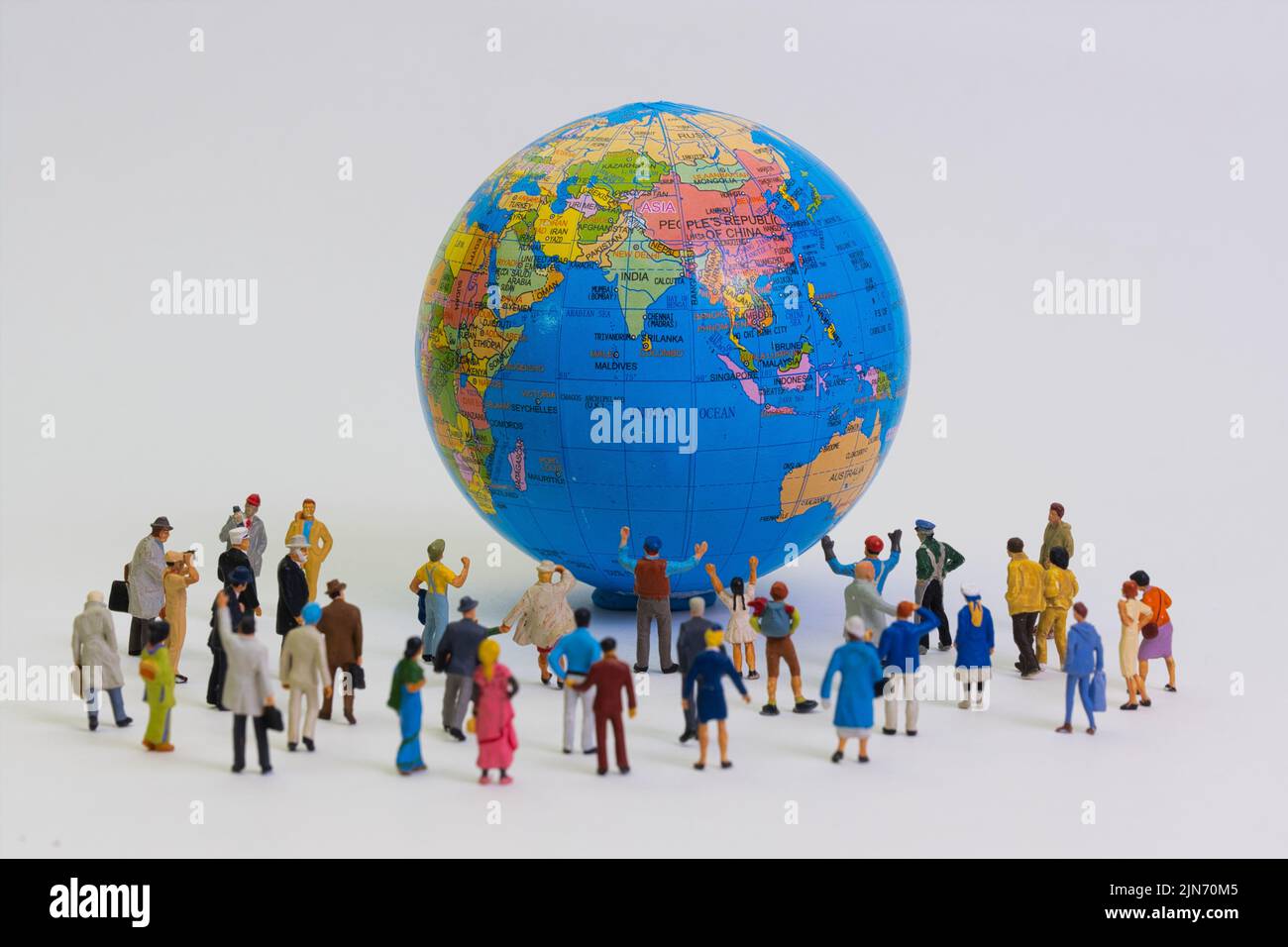 diverse people from all over the world stand happily around a globe ...