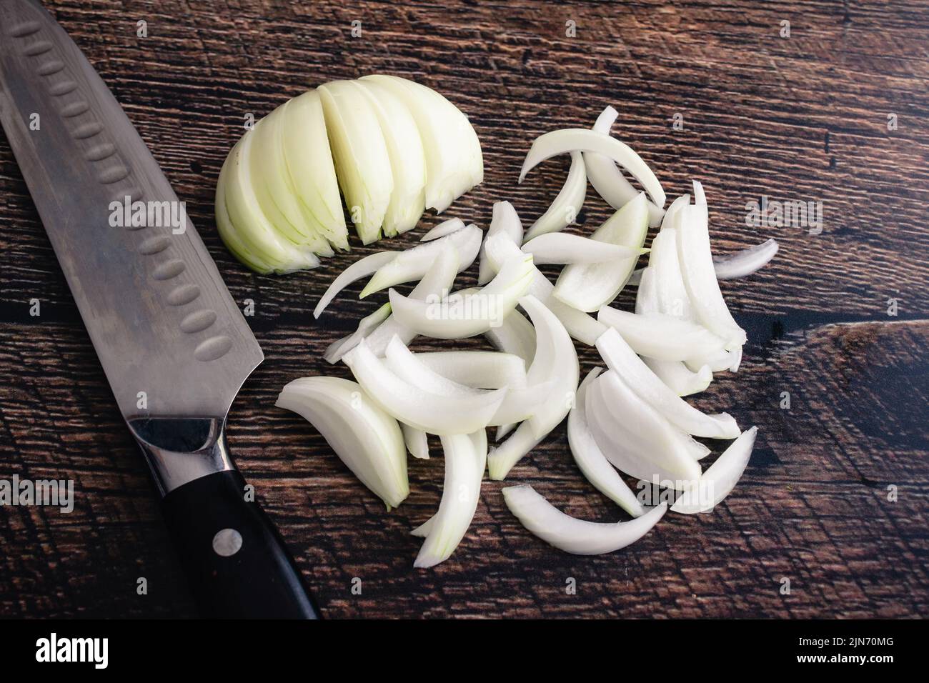 Thinly Sliced Onion on a Dark Wood Cutting Board: Onion sliced into ...