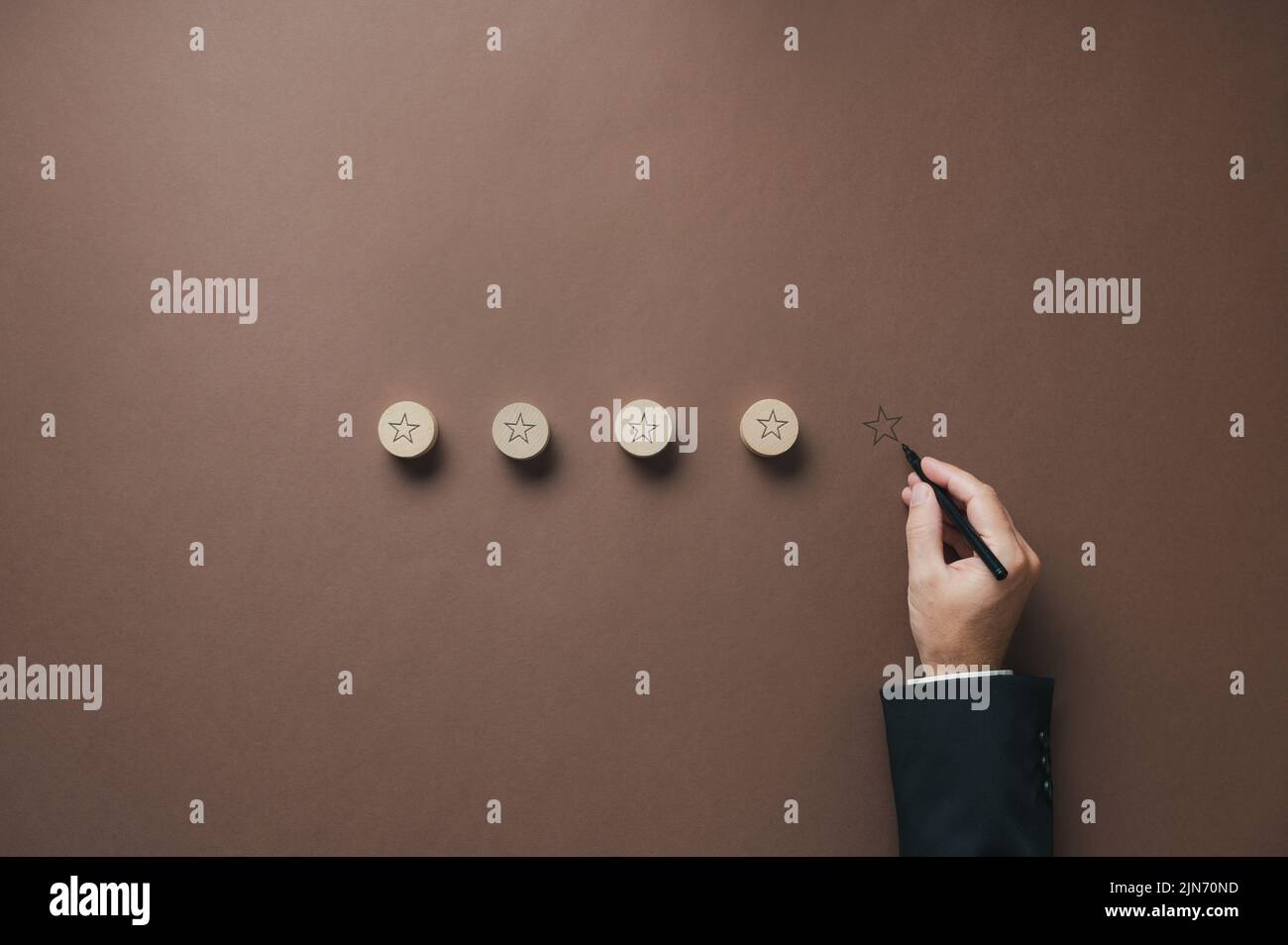 Four stars drawn on wooden cut circles with a hand of a businessman ...