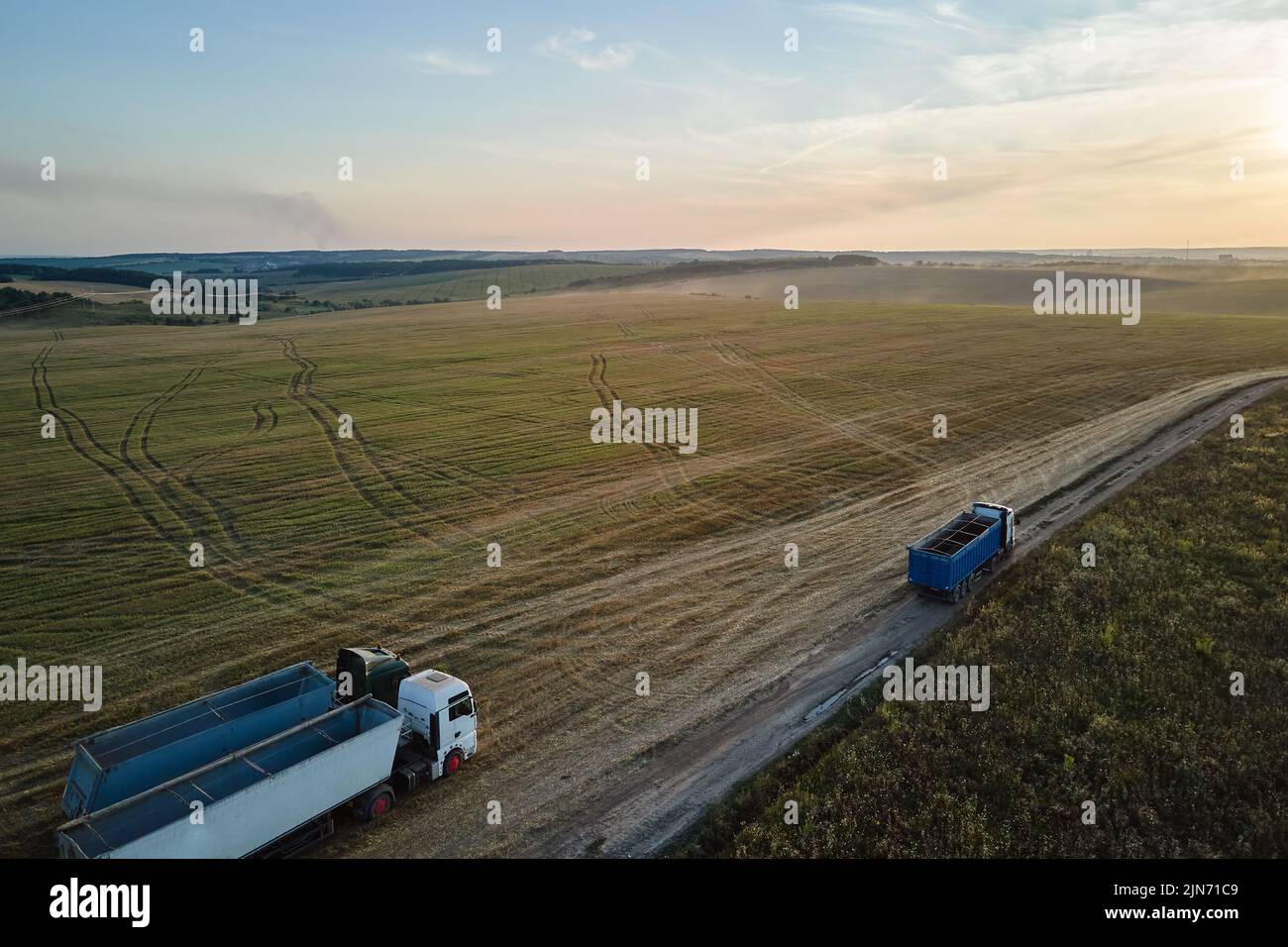 Aerial view of cargo truck driving on dirt road between agricultural ...