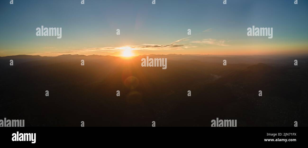 Aerial view of dark mountain hills with bright sunrays of setting sun ...