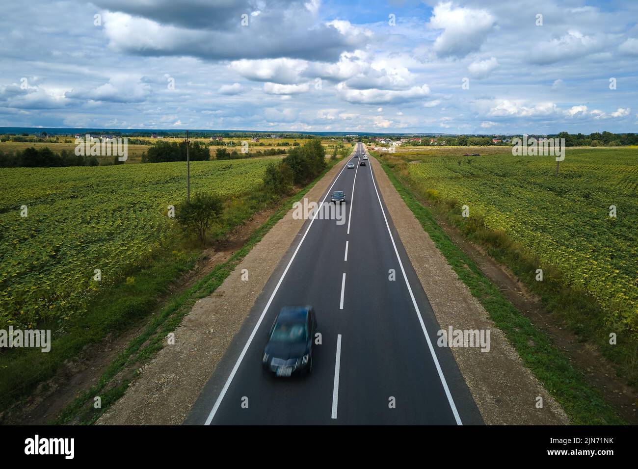 Aerial view of intercity road between green agricultural fields with ...