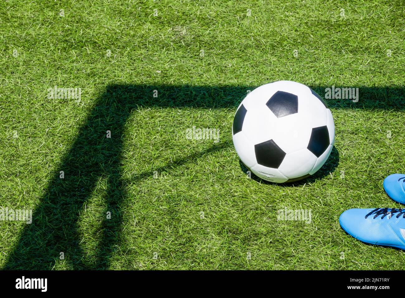 Green artificial turf soccer field with shadow from football goal net ...