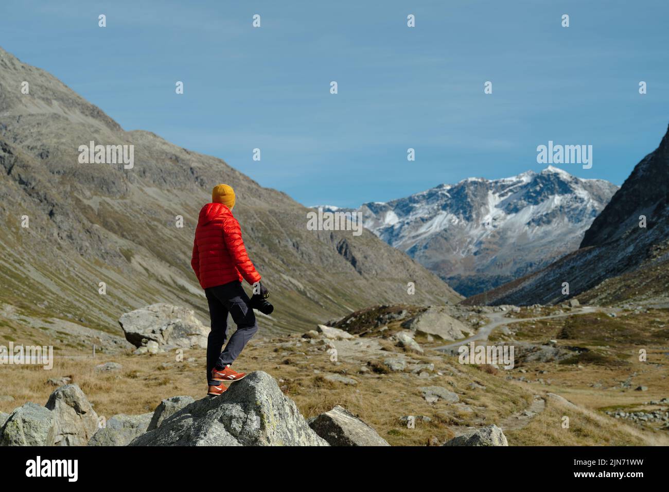 Back view of a tourist man in red jacket and camera standing with a ...