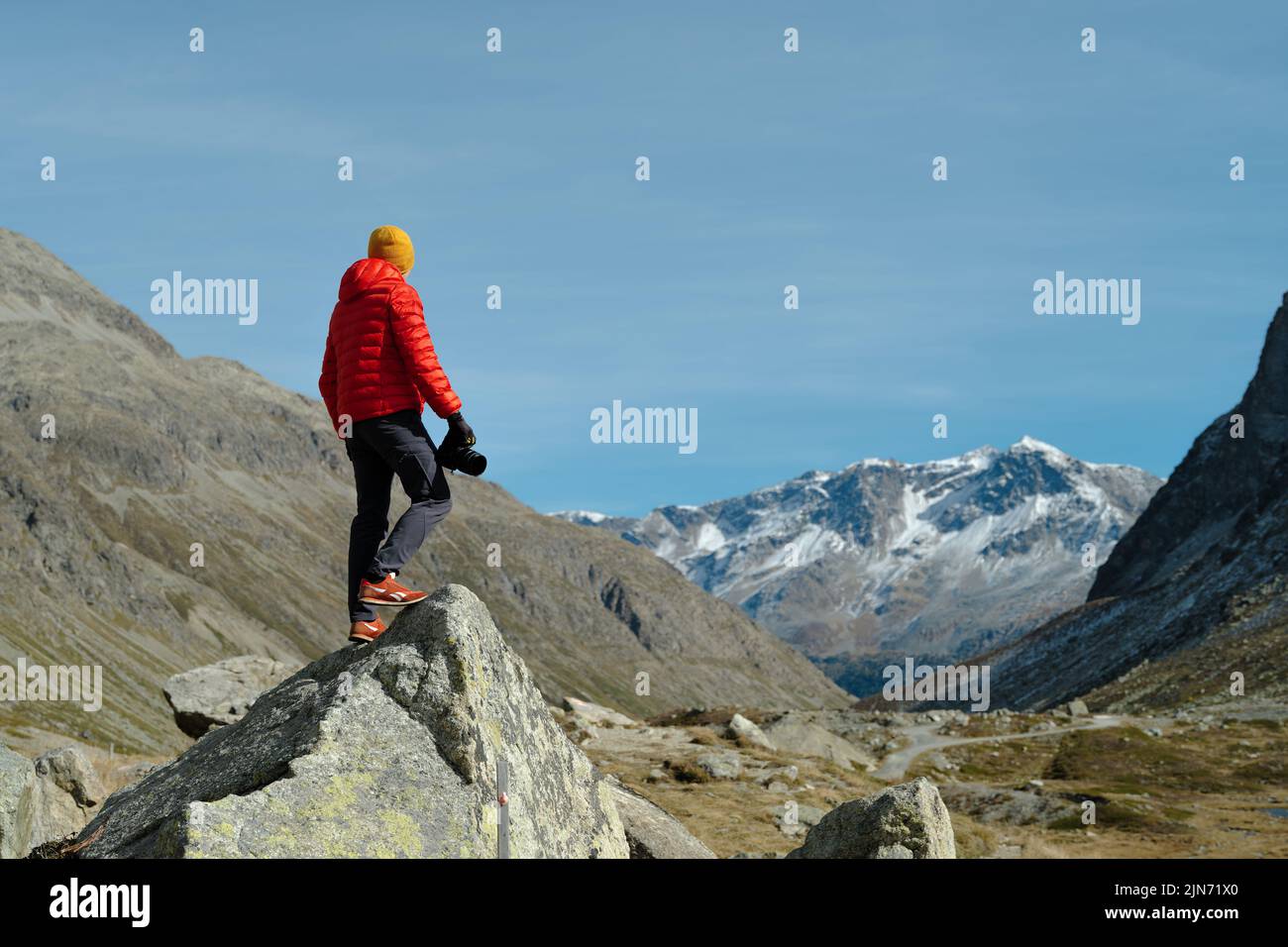 Back view of a tourist man in red jacket and camera standing with a ...